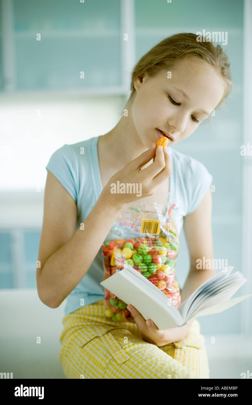 Girl snacking and reading Stock Photo - Alamy