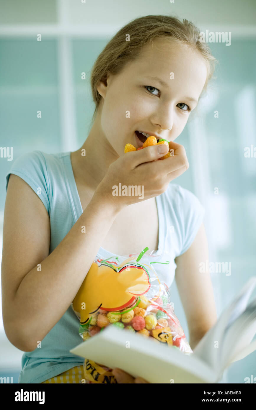 Girl snacking and reading Stock Photo - Alamy