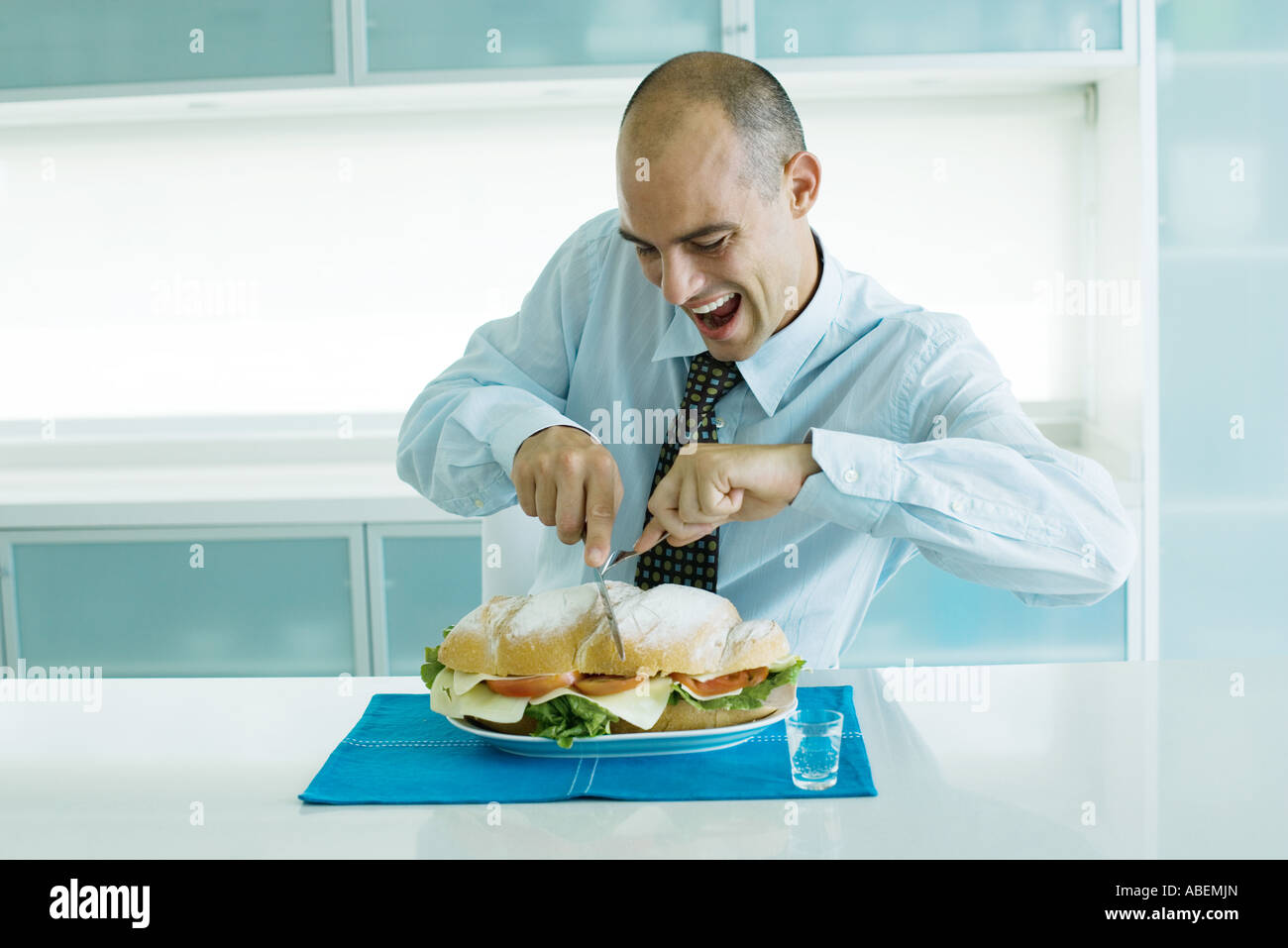 Man cutting into large sandwich with knife and fork Stock Photo - Alamy