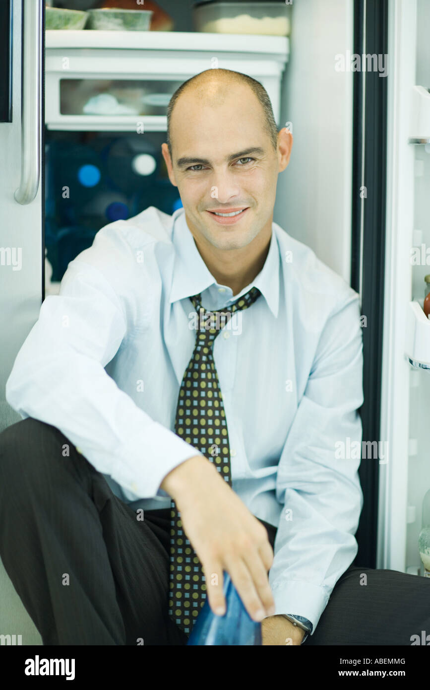 Man sitting in front of open refrigerator, smiling at camera Stock ...