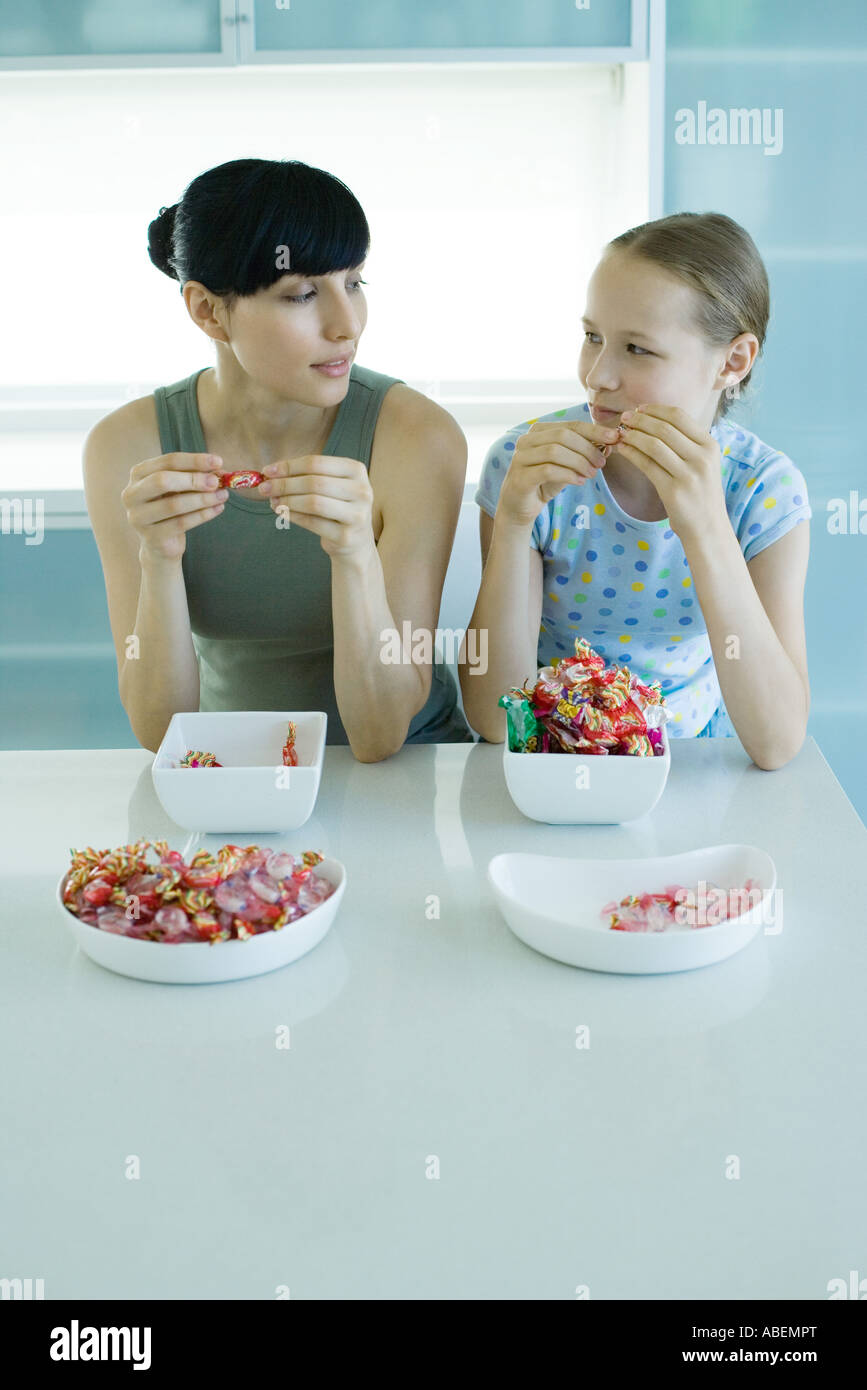 Woman and girl sitting side by side eating bowls of candy Stock Photo ...