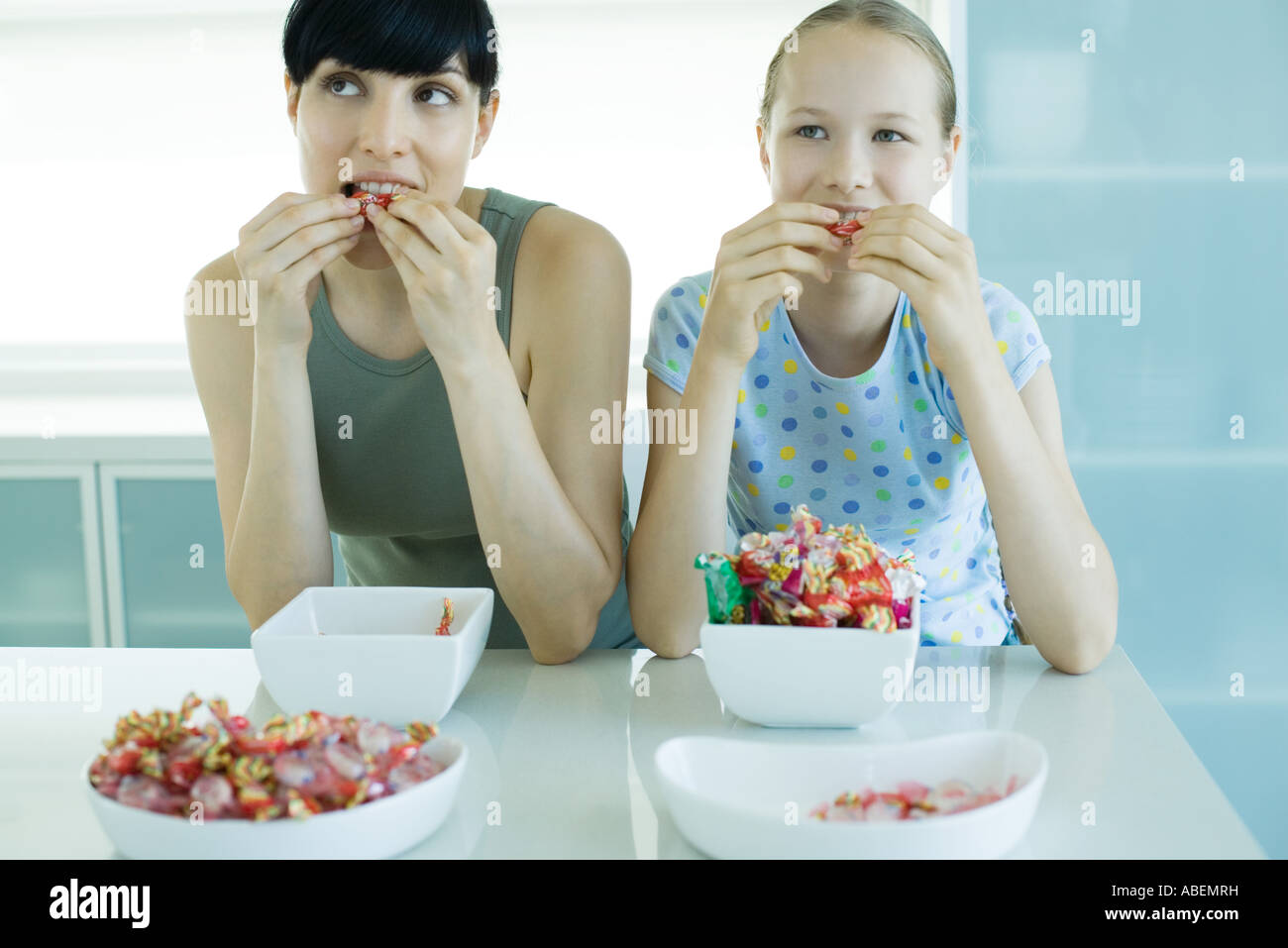 Woman and girl sitting side by side eating bowls of candy Stock Photo ...
