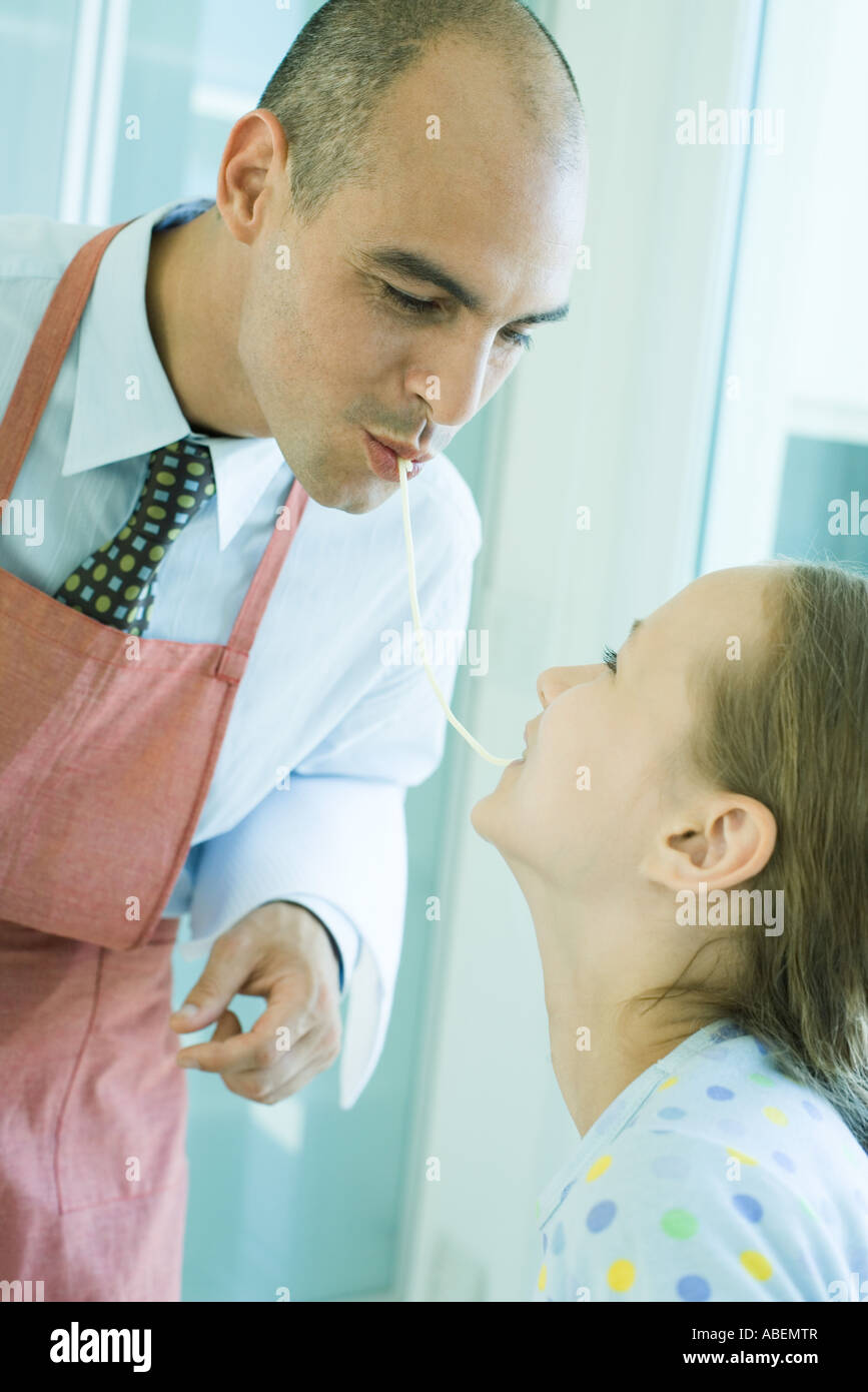 Father and daughter sharing spaghetti noodle Stock Photo - Alamy