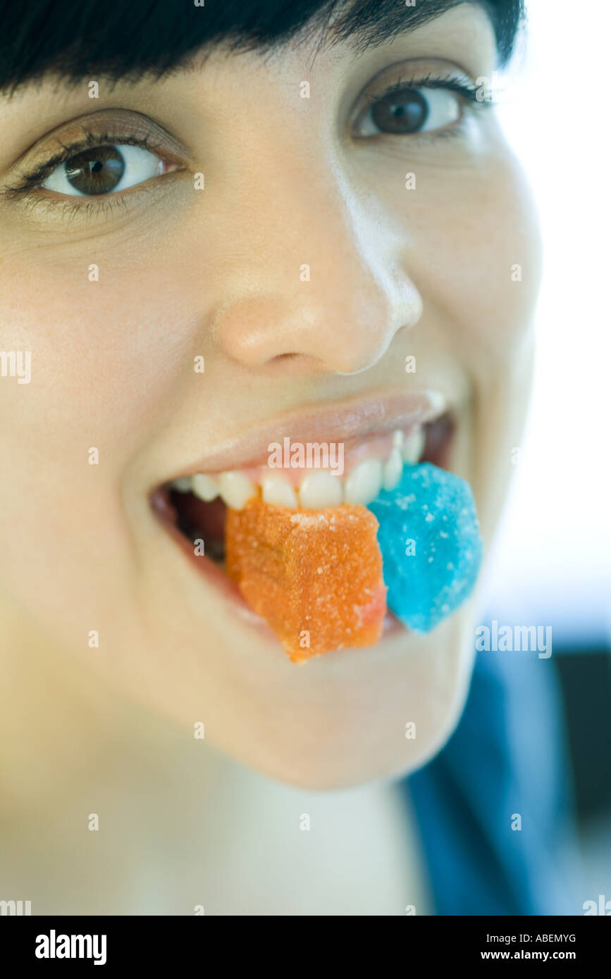 Woman holding pieces of candy between teeth, smiling at camera Stock ...