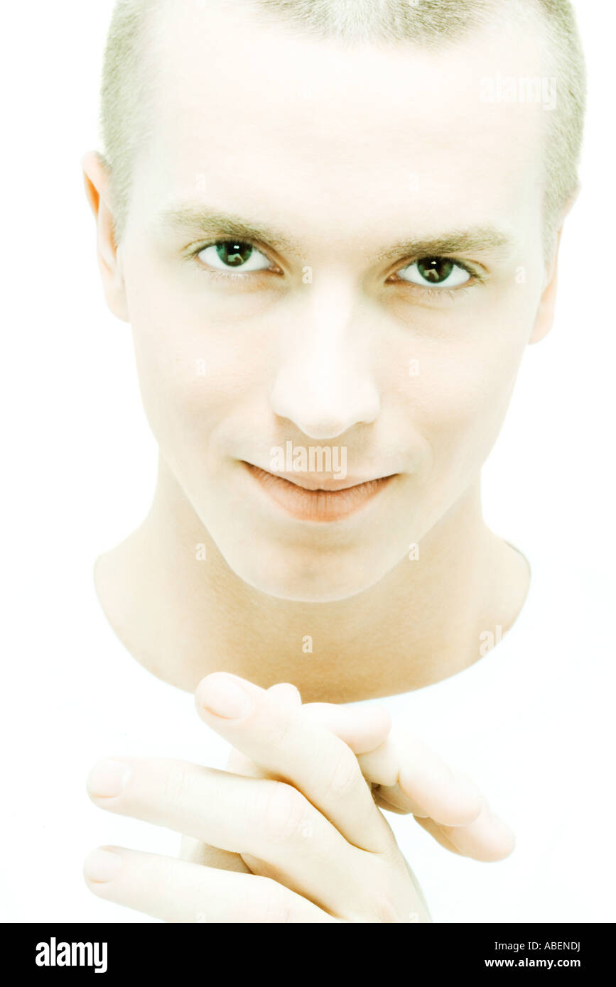 Young man clasping hands, looking at camera Stock Photo - Alamy