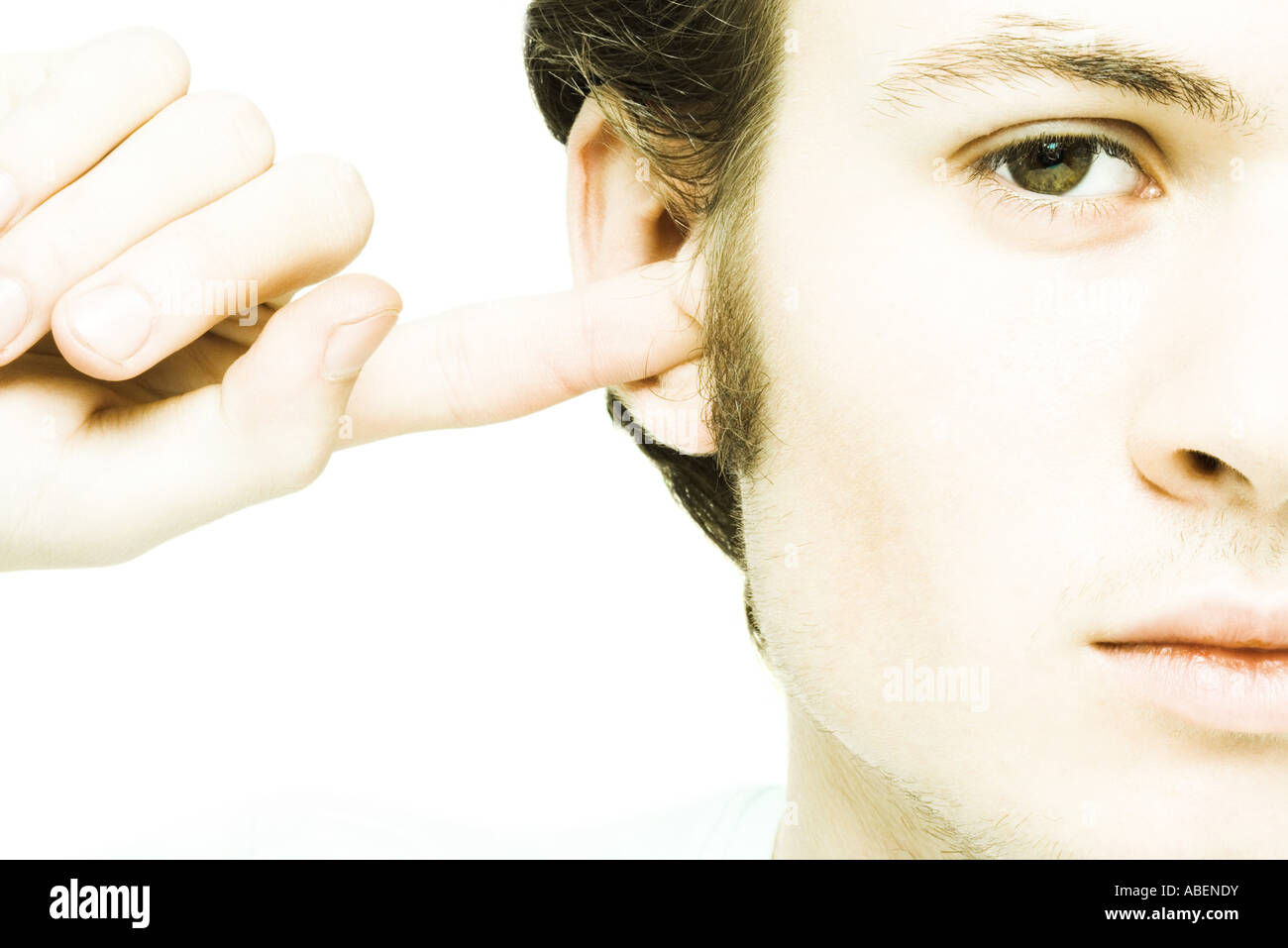 Young man plugging ear with finger Stock Photo - Alamy