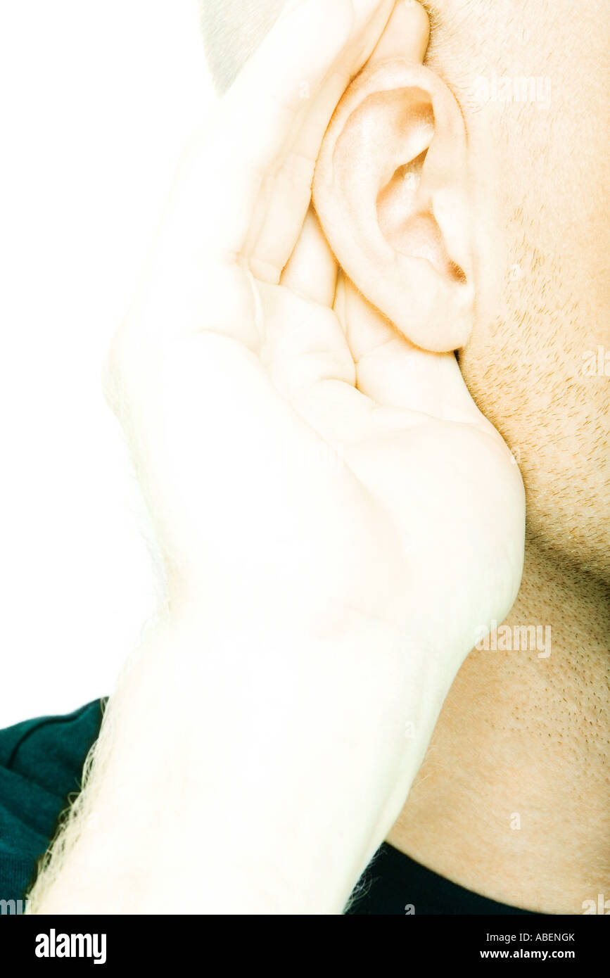 Young man holding hand behind ear, extreme close-up Stock Photo - Alamy