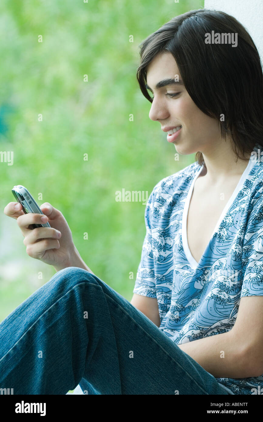 Teen boy looking at cell phone, smiling Stock Photo - Alamy