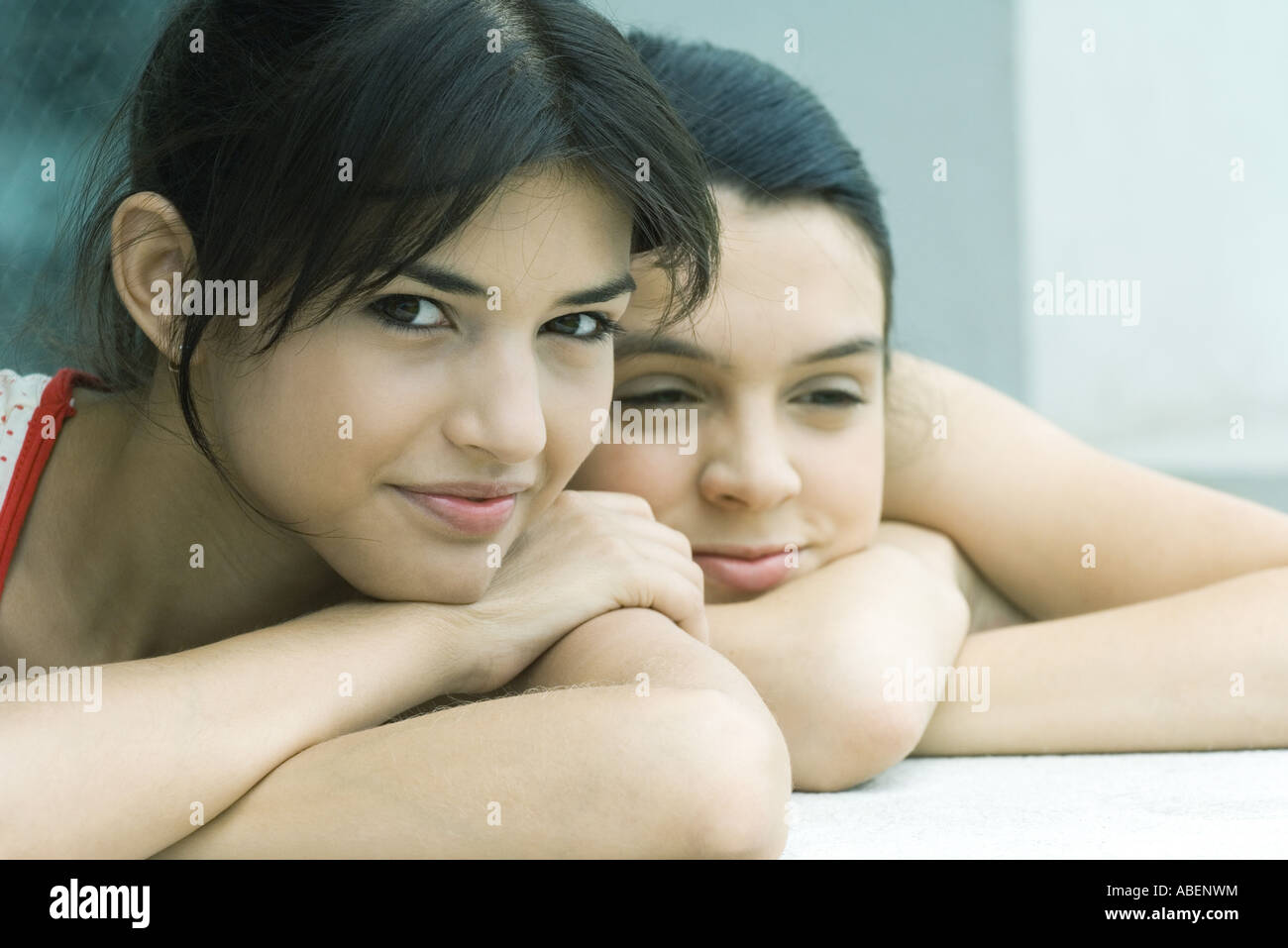 Teen girl and young woman resting heads on arms, smiling Stock Photo ...