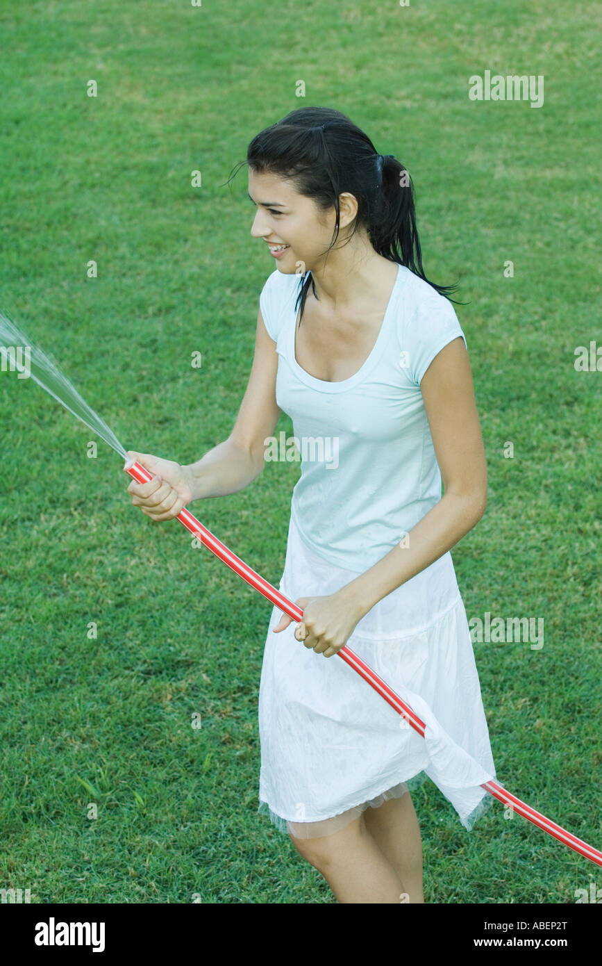 Young woman holding garden hose Stock Photo - Alamy