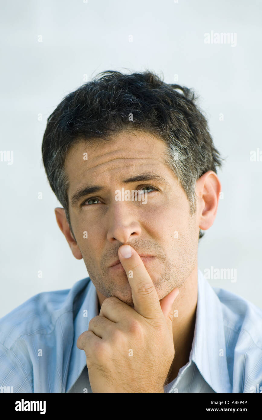 Man, finger over lips, looking up, portrait Stock Photo - Alamy