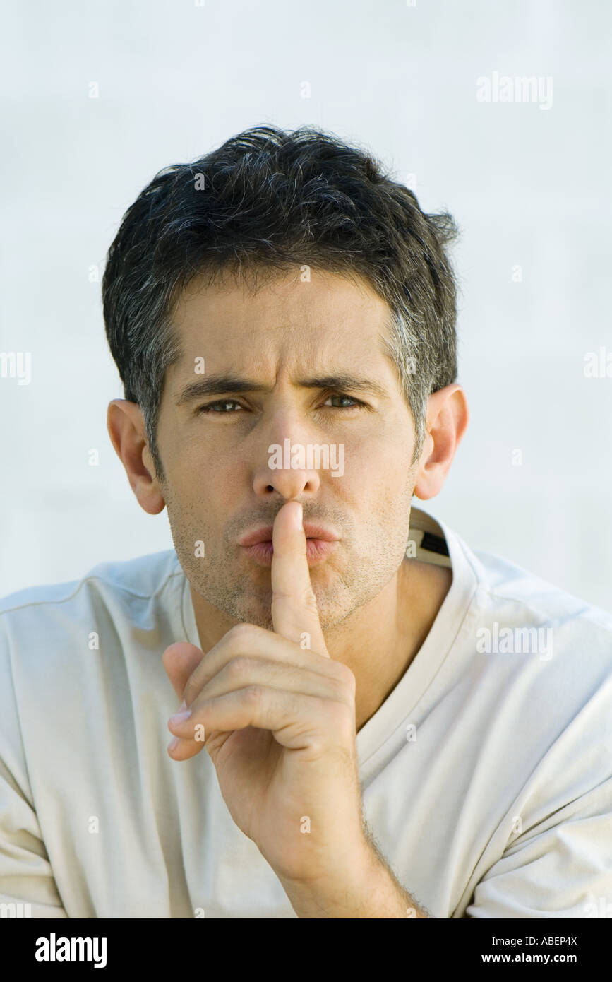 Man, putting finger over lips, portrait Stock Photo - Alamy