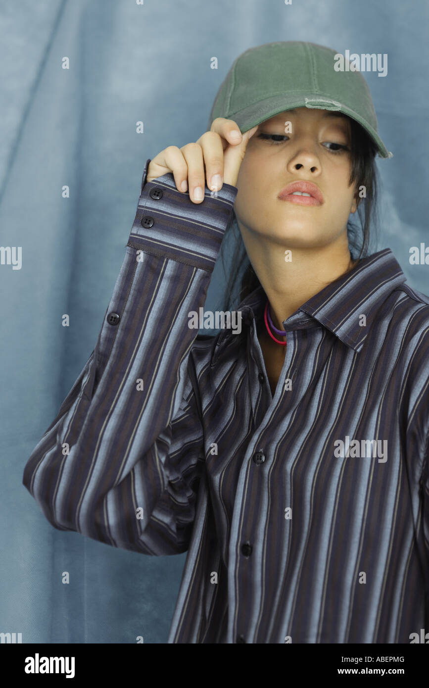 Teenage girl wearing large button down shirt and baseball cap, portrait ...
