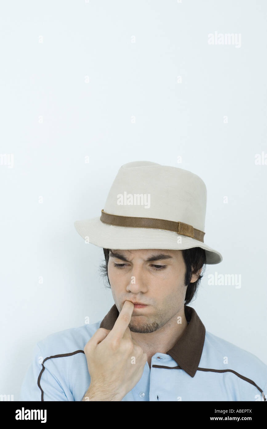 Young man biting finger, looking down Stock Photo - Alamy