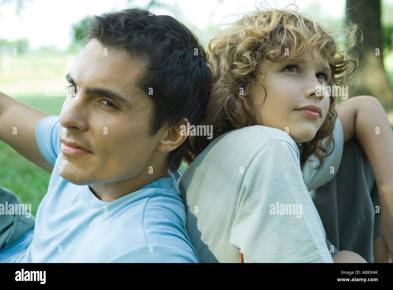 Boy and father sitting back to back Stock Photo - Alamy