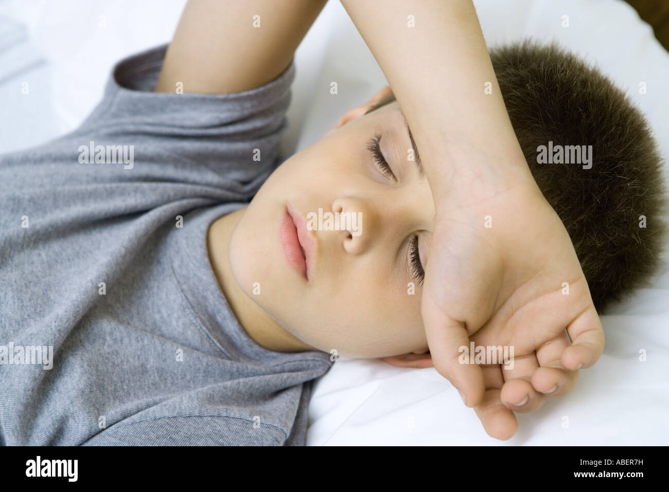 Boy lying down with arm covering forehead Stock Photo - Alamy