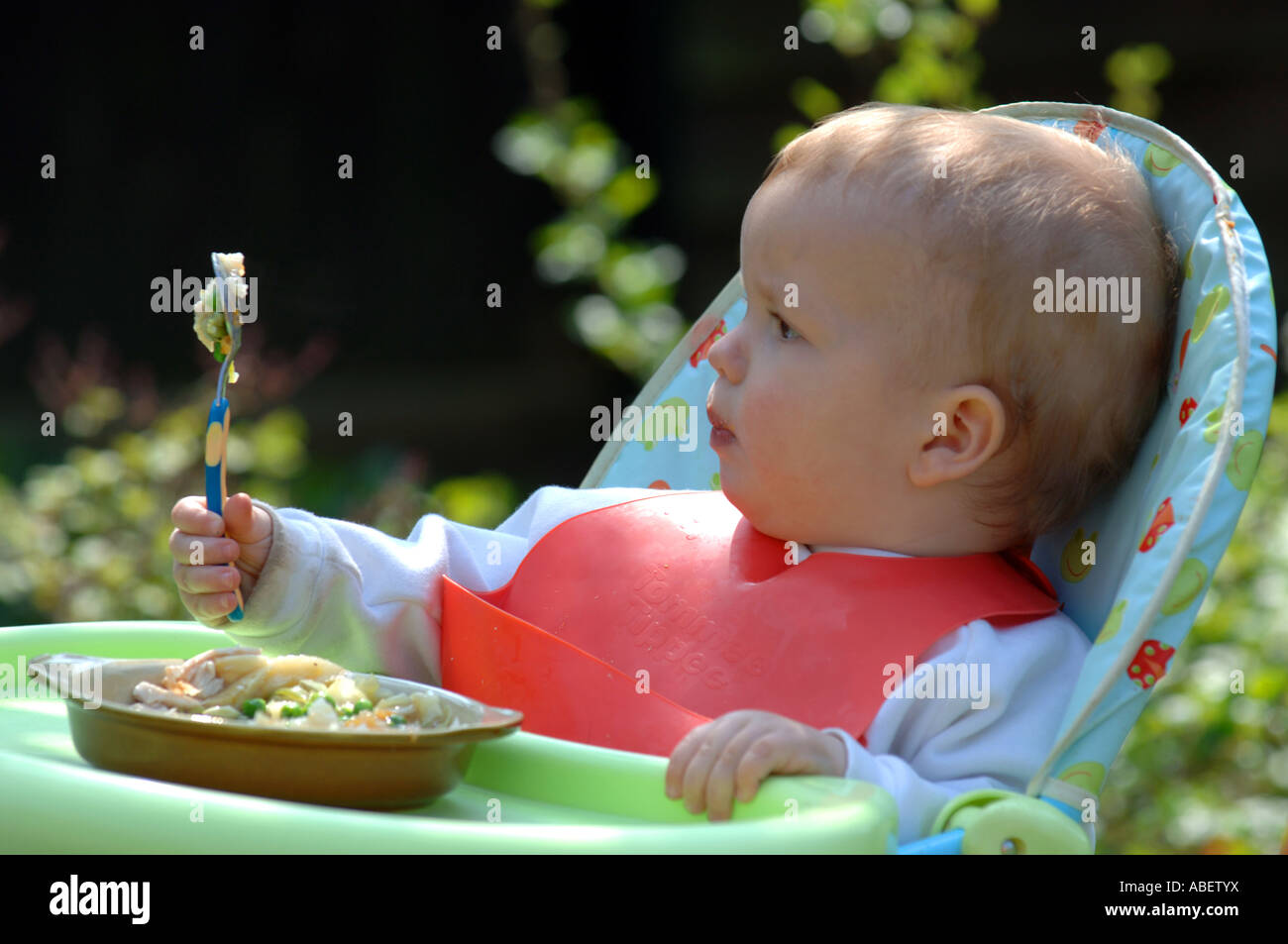 Baby feeding himself solid food Stock Photo - Alamy