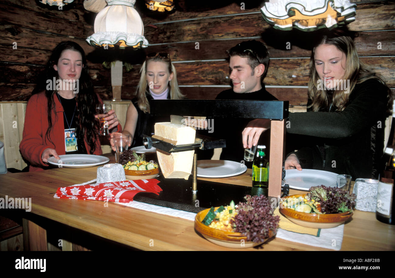 Group of young friends enjoying a cheese raclette afer a good days ...