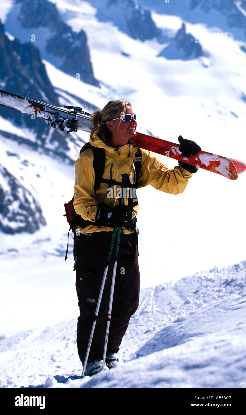 Female skier walking with her skis on her shoulder up a slope Stock ...
