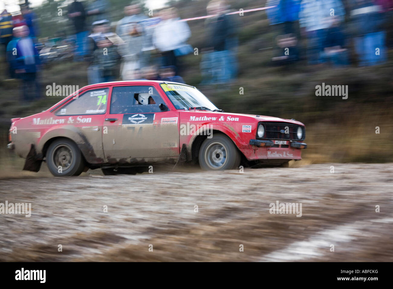 Muddy red Ford Escort rally car driving on gravel stones and mud Stock ...