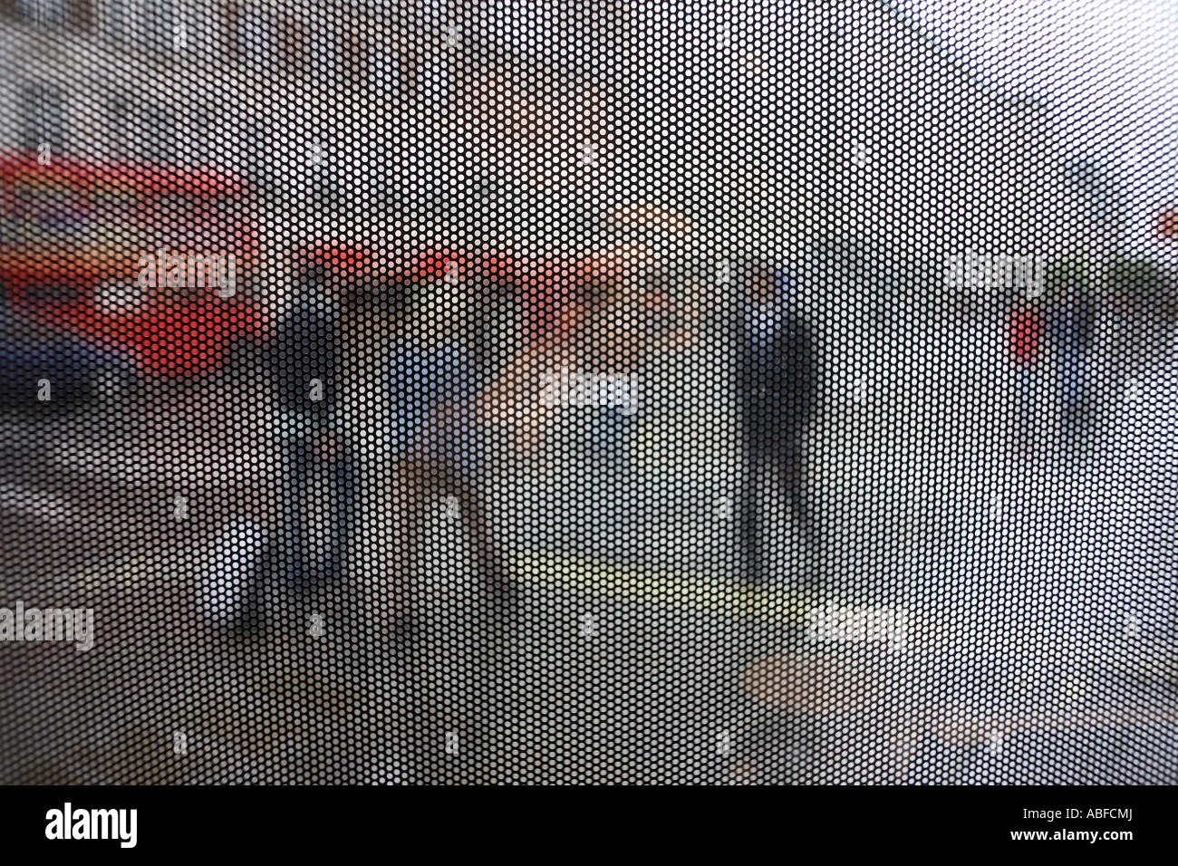 Pedestrians and generic traffic are seen through a window screen ...