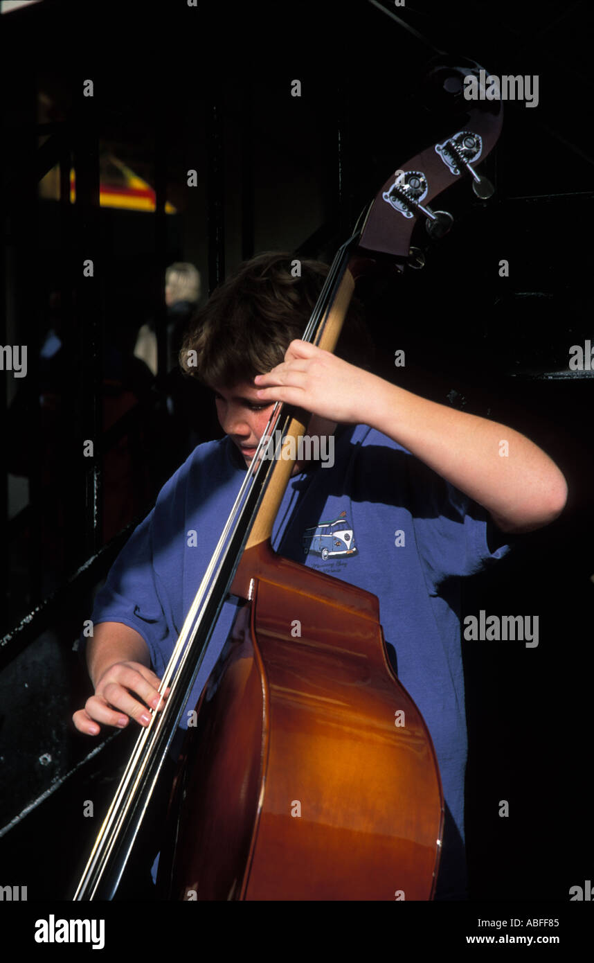 A young bass player playing music in the street of Pike Place Market ...