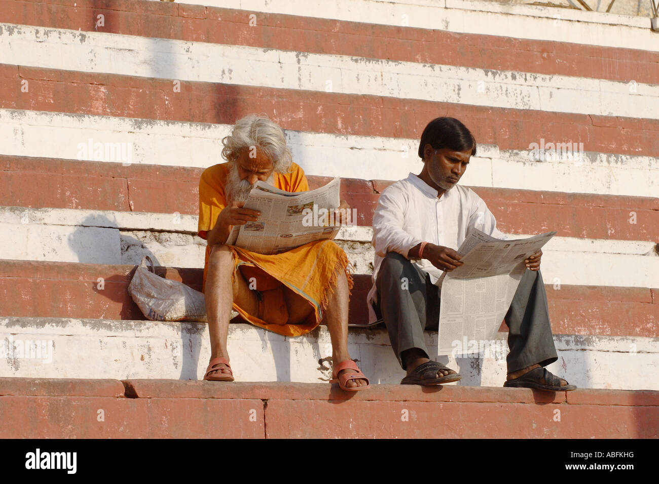 Two men enjoy the 'times of india' on the side of the Ganges river ...