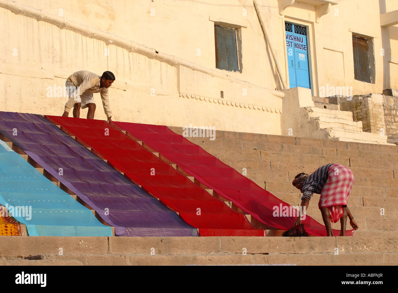 Two men lay out sarees that have just been washed in the river Ganges ...
