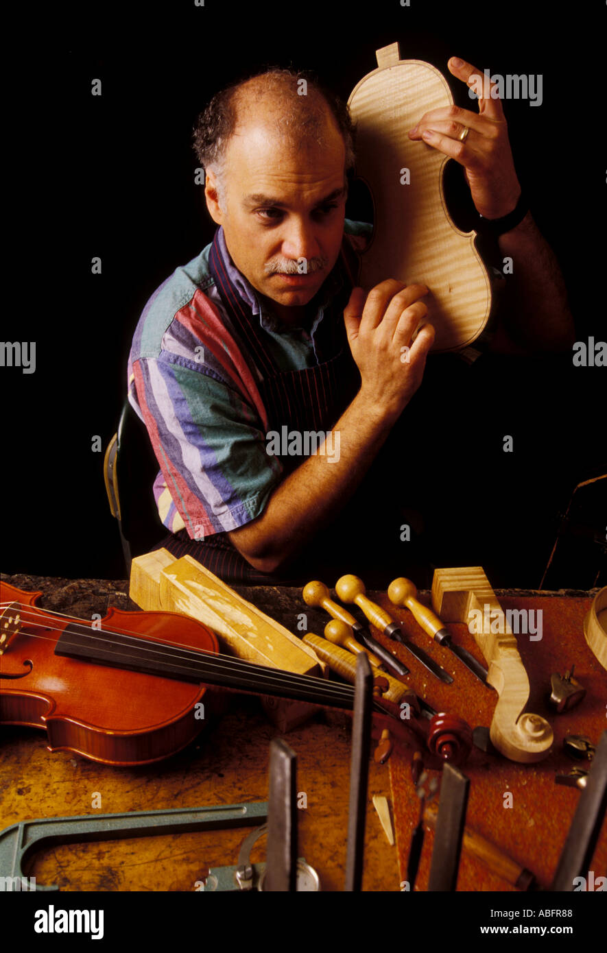 A violinmaker tests the tone of a violin body under construction Stock ...
