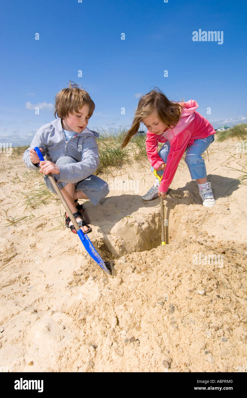 Young Children Digging Hole on Beach Stock Photo - Alamy