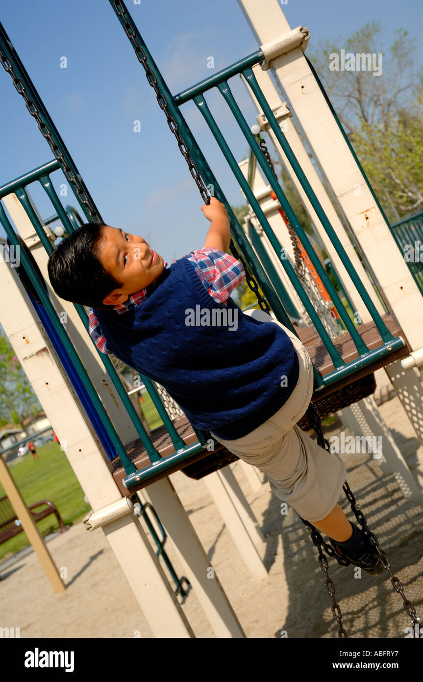 Boy hanging from park equipment Stock Photo - Alamy