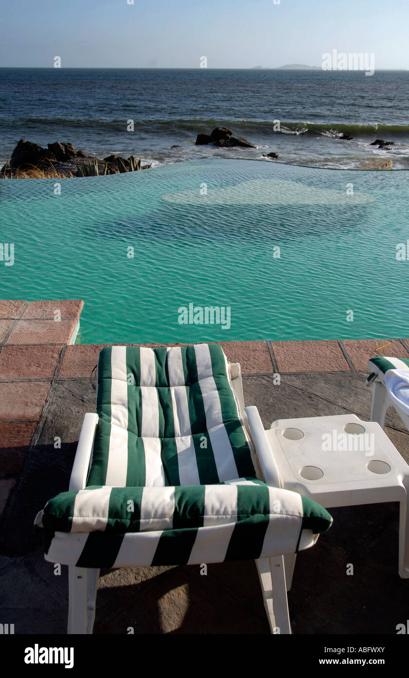 Lounge chairs by a pool and the ocean Stock Photo - Alamy