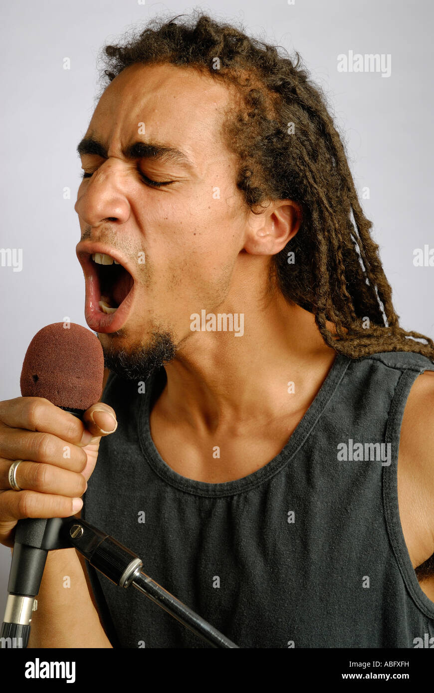 Young black man holding a microphone and singing loudly Stock Photo - Alamy