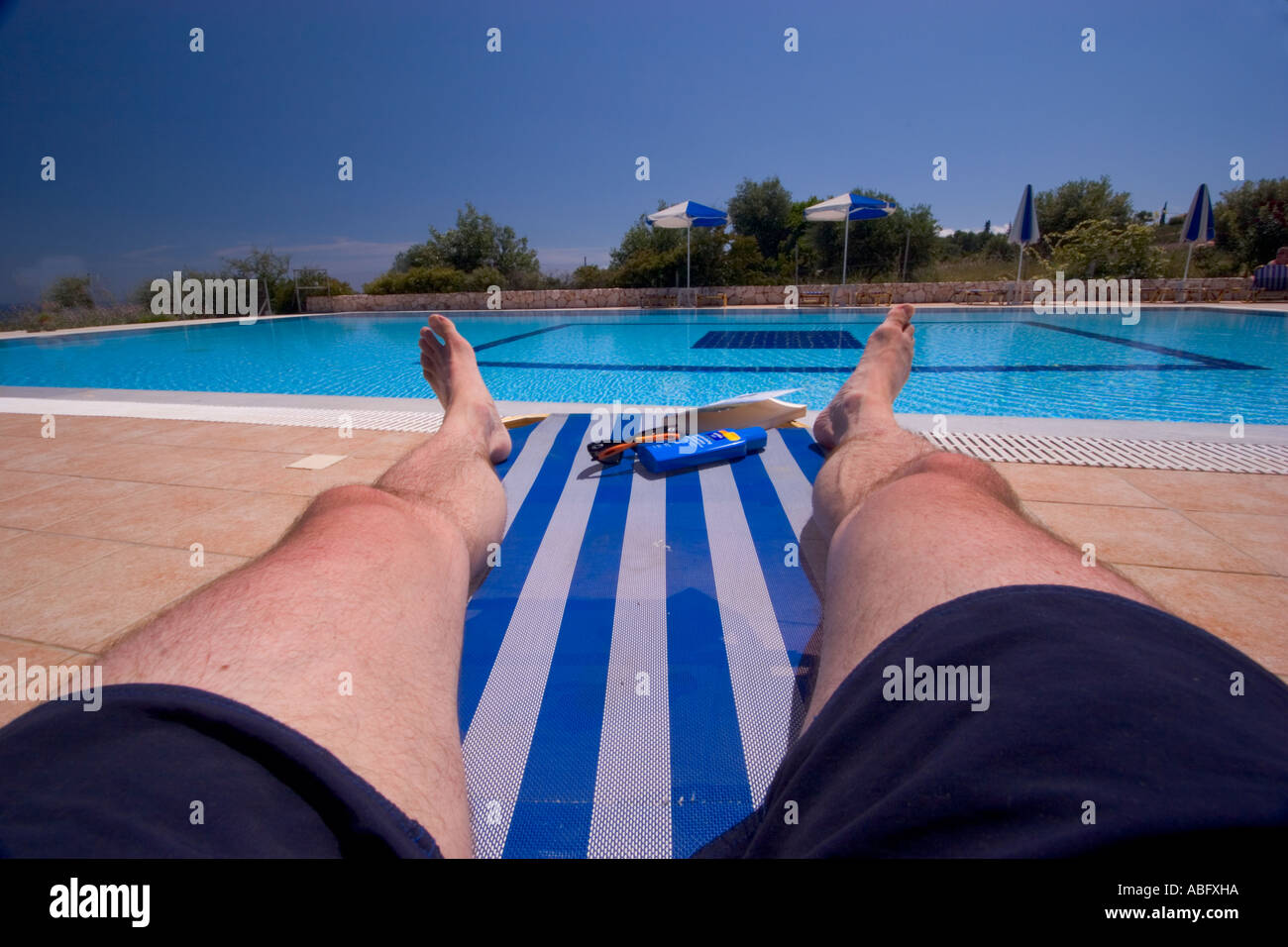 Sunbathers view of empty swimming pool in sun with sun tan cream and ...