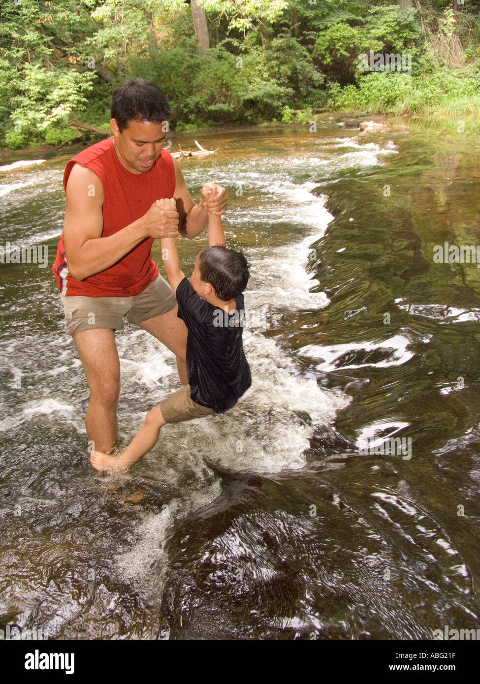 Filipino American man with four year old son wading in stream Stock ...