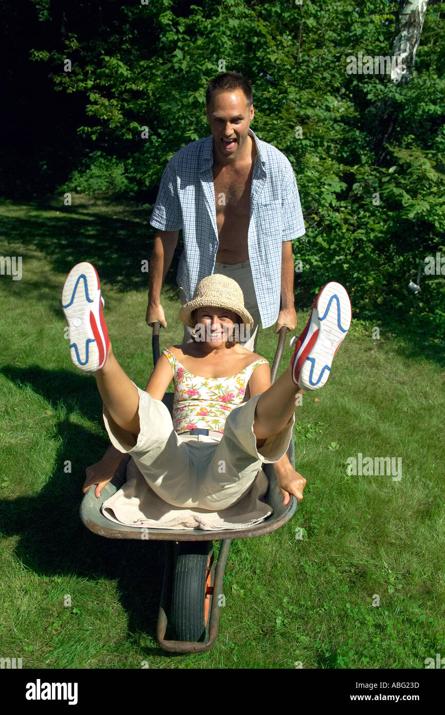 man pushing woman in a wheelbarrow in garden Stock Photo - Alamy