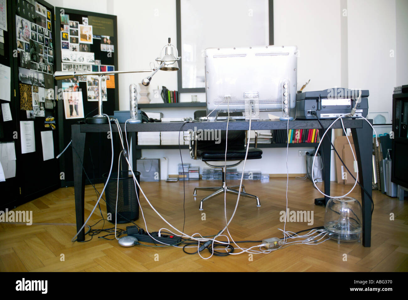 office workstation with desk PC computer cables chair lamp and pinboard ...