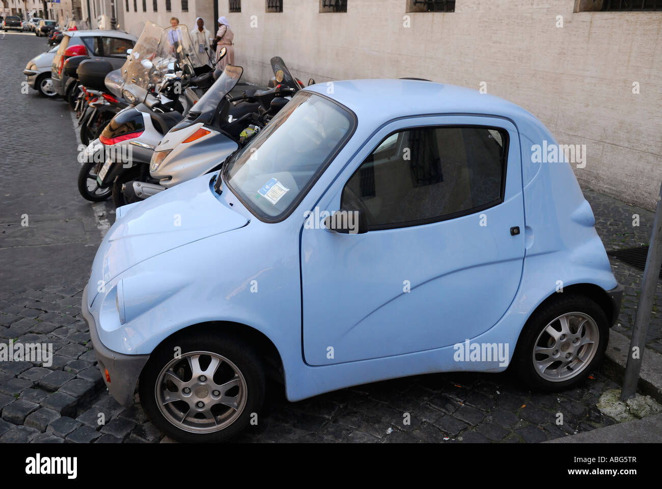 Tiny cute car parked on Rome street with motorbikes Italy Stock Photo ...