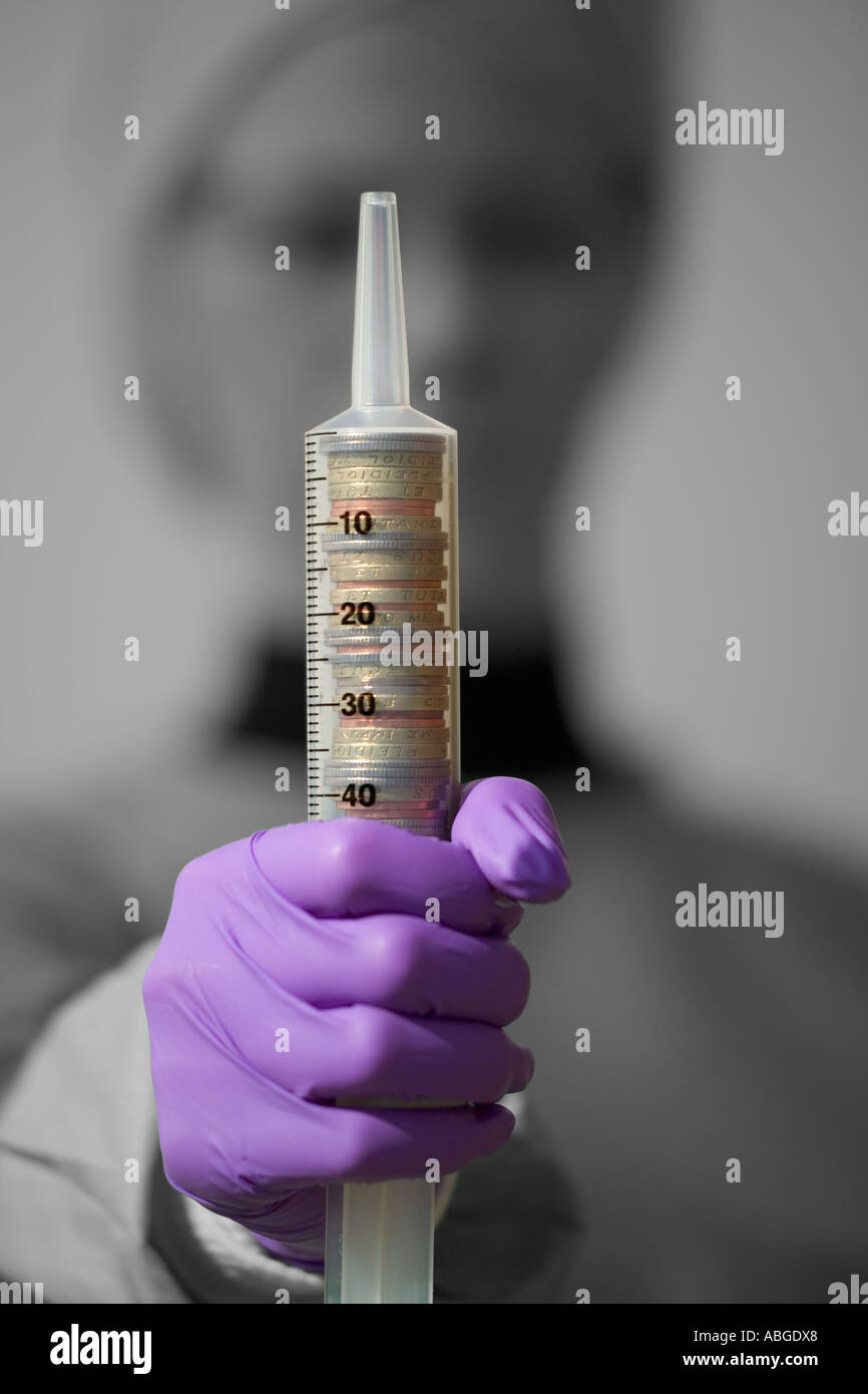 Medical NHS Cash injection coins in syringe held by medic Stock Photo ...