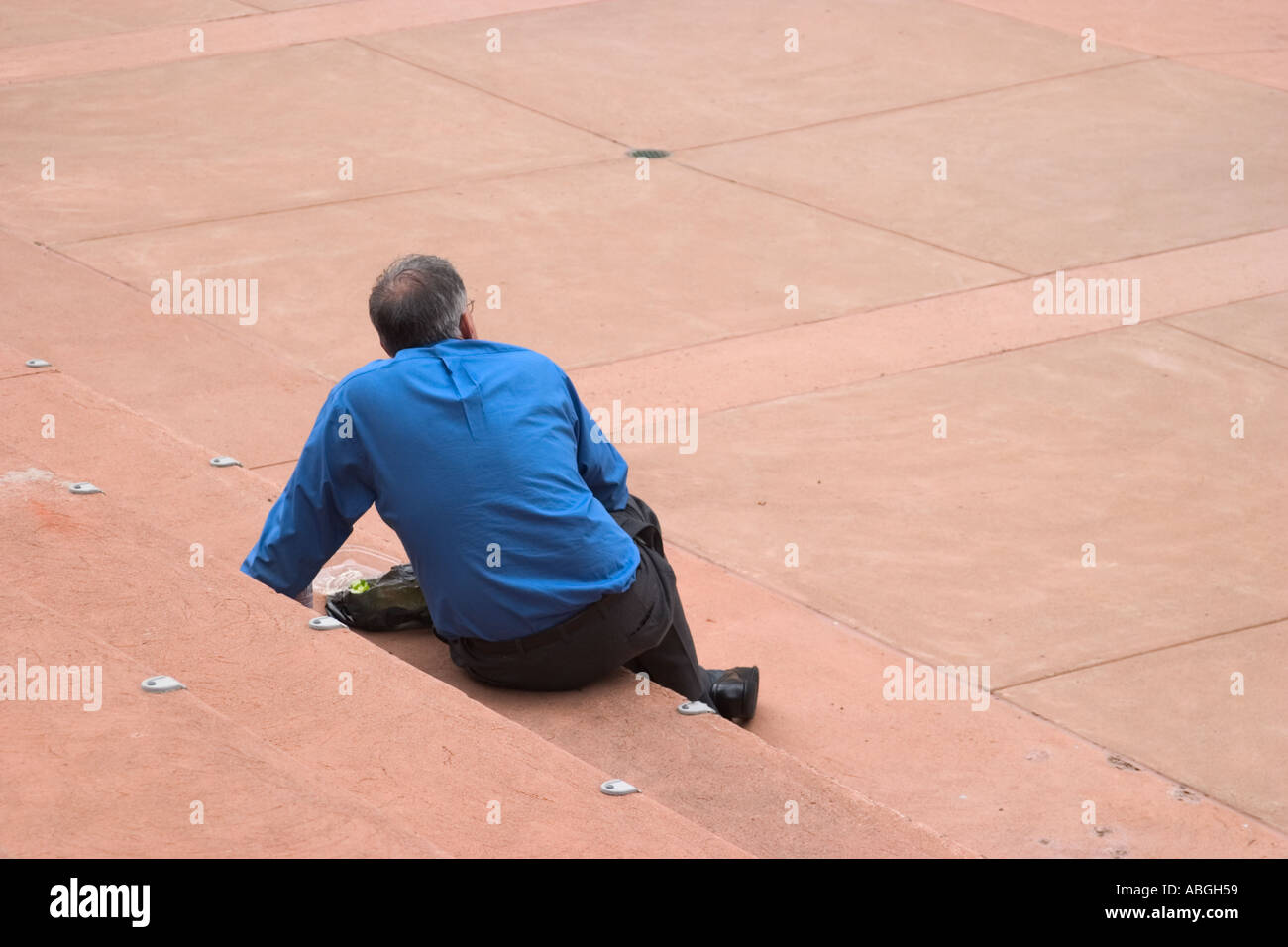 Man sitting alone on concrete stairs eating lunch Stock Photo - Alamy