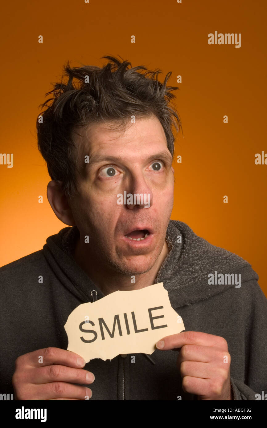 Scary man holding a sign that says "Smile Stock Photo - Alamy