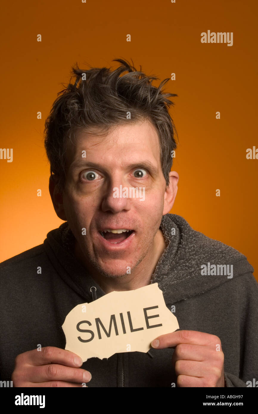 Scary man holding a sign that says "Smile Stock Photo - Alamy