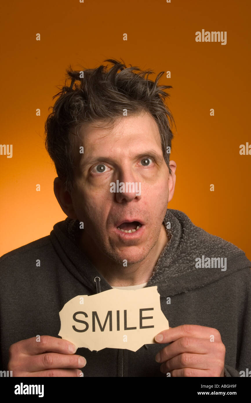 Scary man holding a sign that says "Smile Stock Photo - Alamy