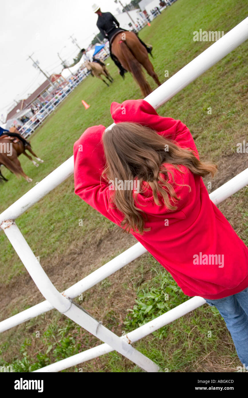 Young girl leaning on a railing as she watches a horse show at a ...