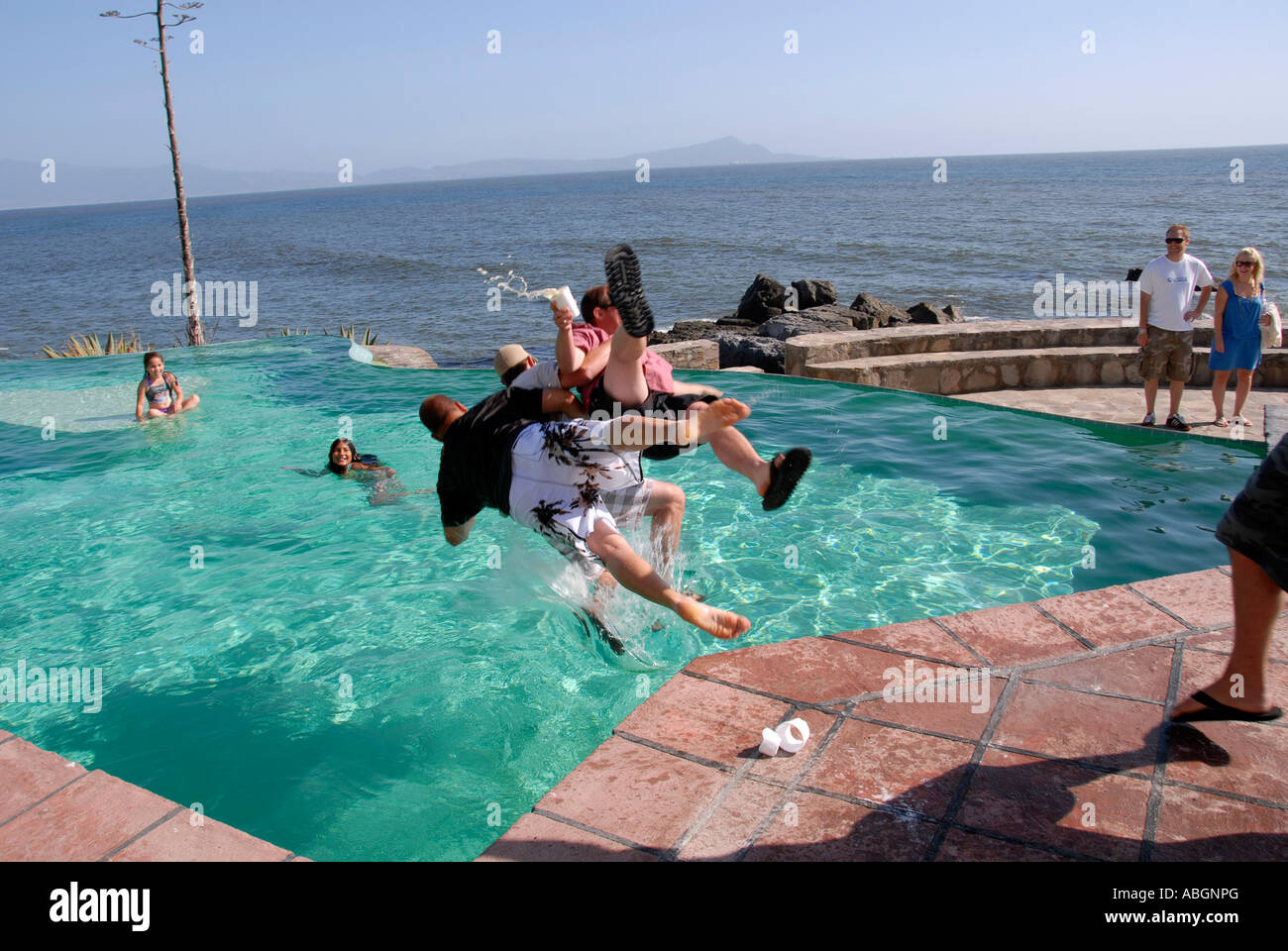 Young men wrestle and pull each other into a pool Stock Photo - Alamy