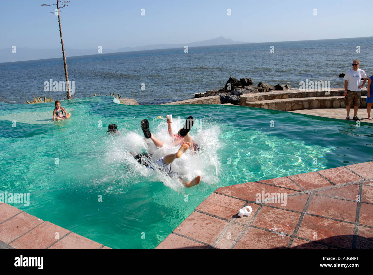 Young men wrestle and pull each other into a pool Stock Photo - Alamy