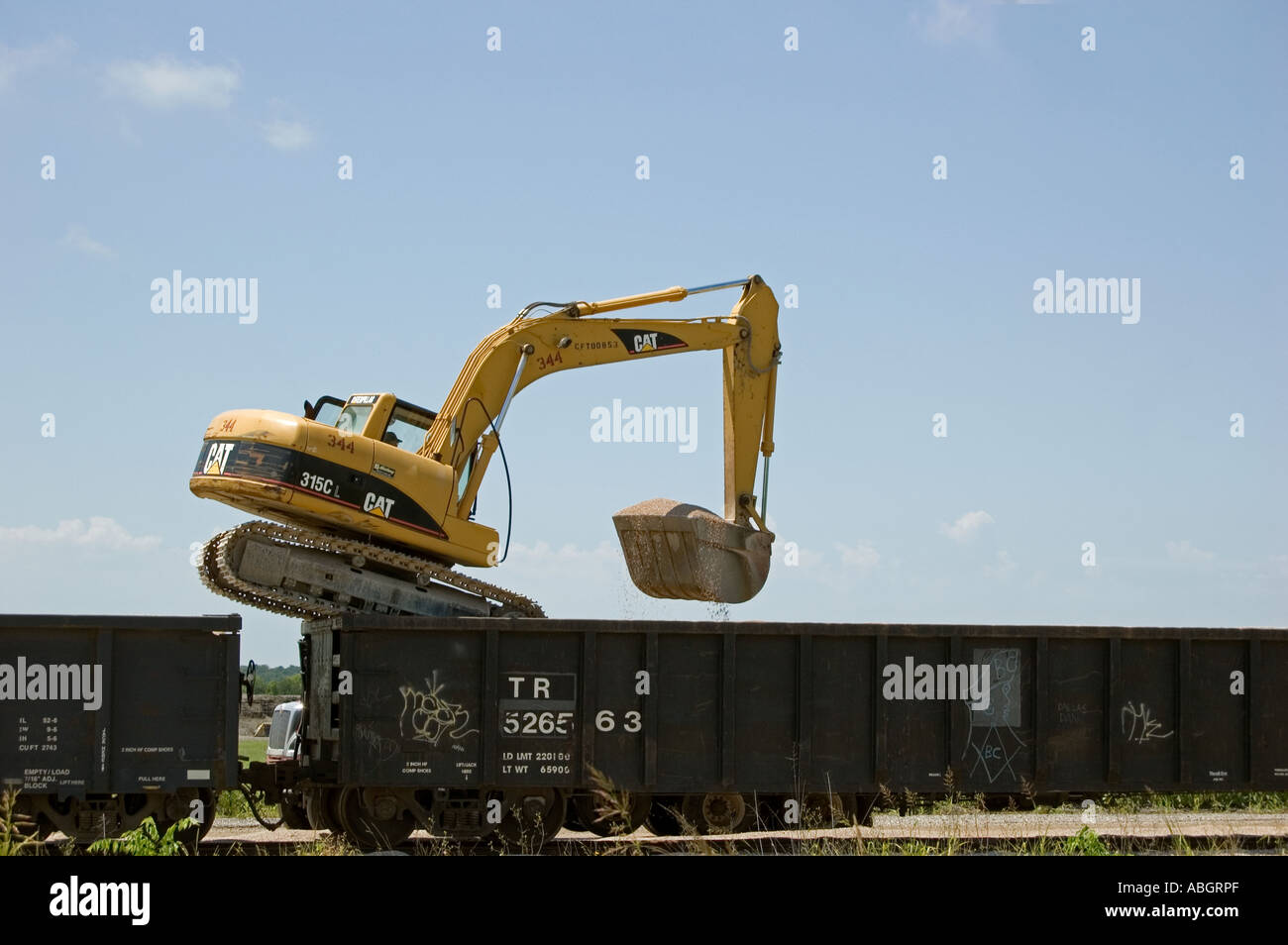 Tractor unloading gravel from train car Stock Photo - Alamy