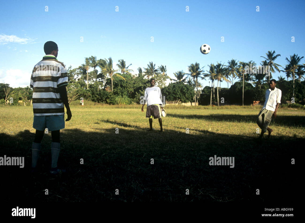 Three boys playing football or soccer in Inhaca Island in Bay of Maputo ...