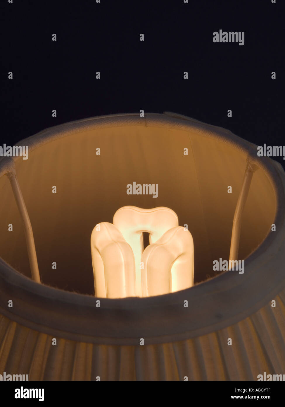 Low energy saving stick light bulb lit up in white lamp shade from ...