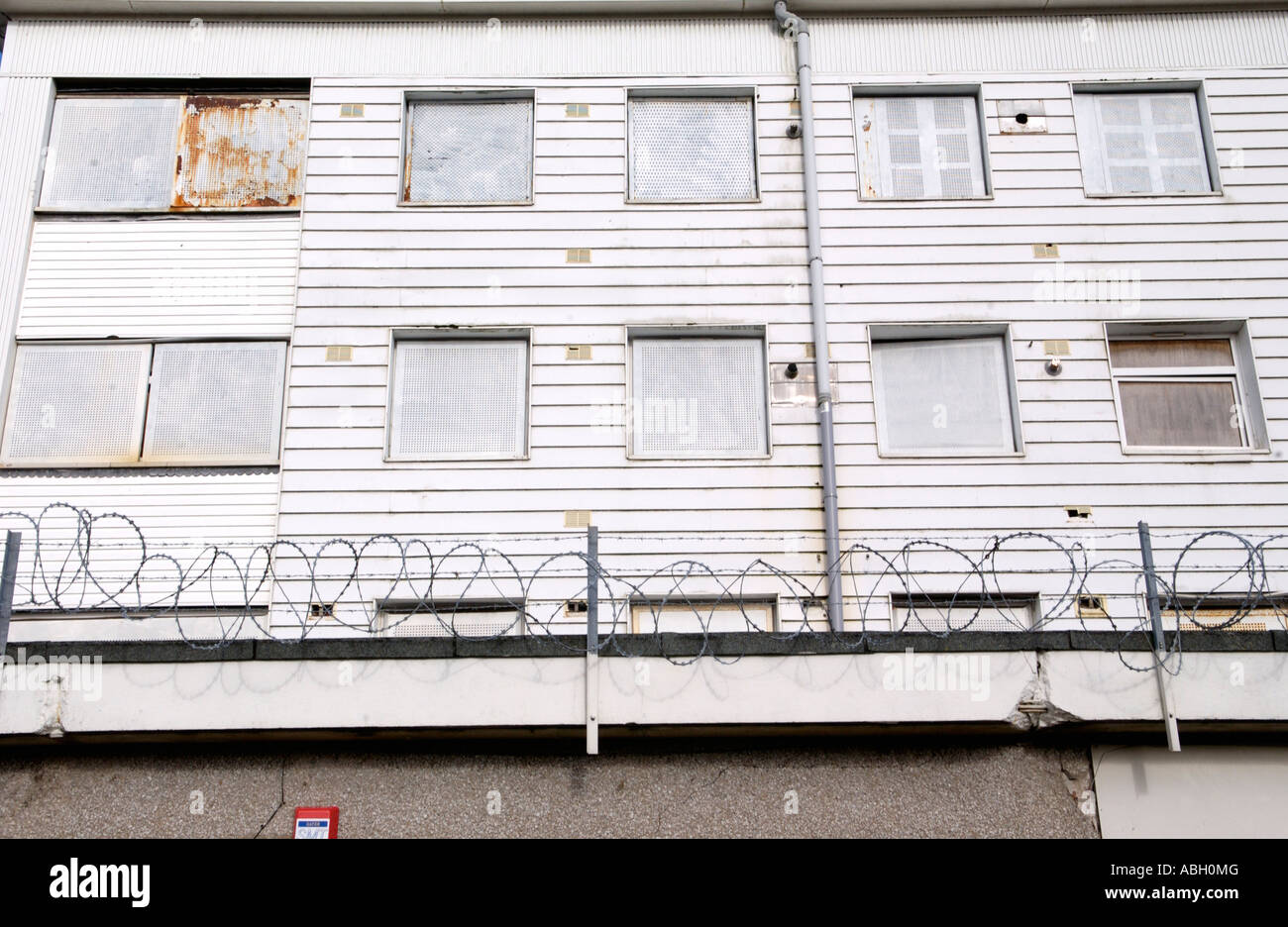 Derelict block of flats boarded up on run down shopping centre with ...